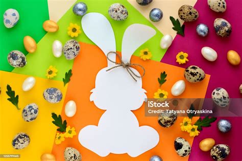 토끼 토끼는 종이 메추라기 계란 잡종 색칠 흰색 사탕과 화려한 기하학적 배경에 누워 작은 노란색 꽃에서 잘라 부활절의 창조적 인 트렌드 개념 공간을 복사합니다 0명에 대한
