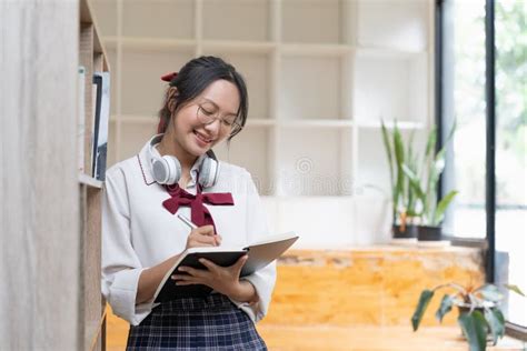 Young Female Student Doing Assignments In Library Asian Woman Taking