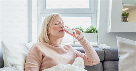 여자는 독감에 걸렸고 그녀는 자신을 돕기 위해 비강 스프레이를 사용하고 있습니다 비강 스프레이를 사용하는 여성 감기에 도움이