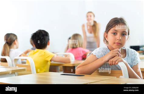 Positive Tween Schoolgirl Sitting At School Desk At Lesson In Class