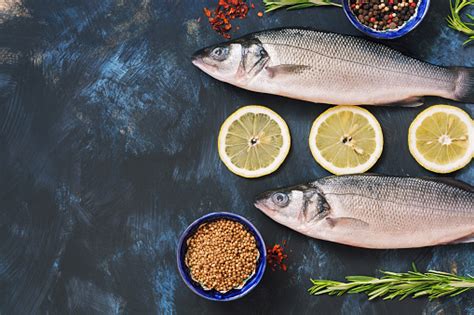 신선한 생선 농 어와 요리재료 레몬 로즈마리 피망 옻나무 고 수 파프리카 파란색 바탕에 원시 물고기입니다 보기 상위 공간을 복사 합니다 개념에 대한 스톡 사진 및 기타