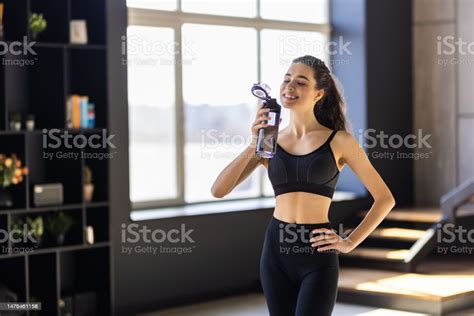 운동복을 입고 건강 음료 유청 단백질 담수 또는 커피가 든 셰이커를 들고 목에 흰 수건을 들고 있는 스포티한 아름다운 웃는