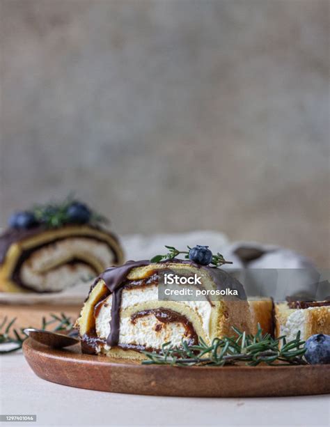초콜릿 유약 블루베리 로즈마리로 장식된 초콜릿과 크림 치즈를 곁들인 스폰지 케이크 롤 양피지 가벼운 배경 비스킷 스위스 롤 거품