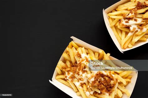 검은 표면에 종이 상자에 치즈 소스와 양파와 감자 튀김 상단보기 평평한 평신도 위에서 오버 헤드 공간을 복사합니다 0명에 대한