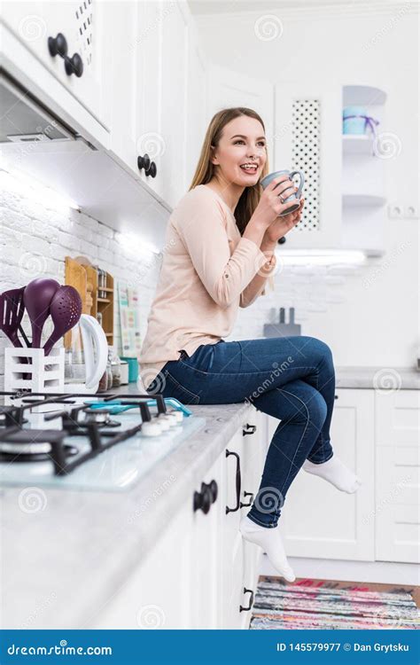Молодая счастливая женщина пьет кофе на кухне утром Стоковое Изображение изображение