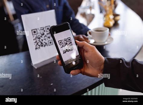 Mid Section Of Man Making A Payment By Scanning Qr Code From Smartphone At A Cafe Stock Photo