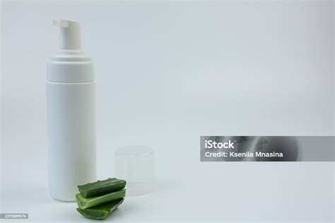 피부에 영양을 공급하고 수분을 공급하고 피부를 청소하기위한 디스펜서가있는 흰색 폼 클렌저의 클로즈업은 흰색 배경에 서 있으며 그 옆에는 텍스트를 위한 공간이 있는 알로에