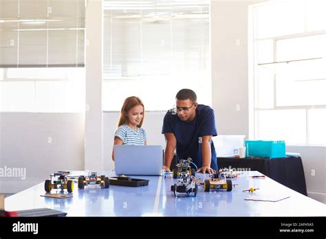 Female Student With Teacher Building Robot Vehicle In After School Computer Coding Class Stock