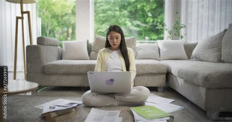 밝은 거실에서 바닥에 앉아 노트북으로 원격 팀과 공동 작업하는 여성 Vídeo De Stock Adobe Stock