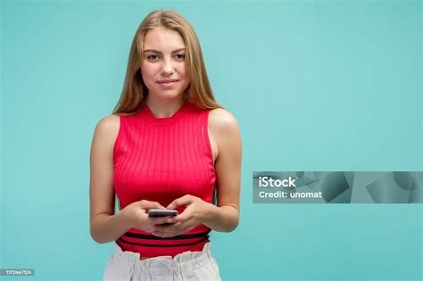 급여에 대해 알리는 문자 메시지를 받고 좋은 소식을 기뻐하고 휴대 전화를 응시하고 행복에서 적극적으로 제스처를 하고 실내에서 혼자 서있는 것을 기쁘게 생각합니다 가을에 대한