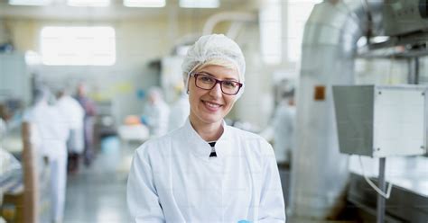 멸균 천을 입은 젊은 즐거운 아름다운 여성 노동자가 태블릿을 들고 공장 생산 라인 근처에서 카메라를 향해 웃고 있다 사진 Unsplash의 세르비아 이미지