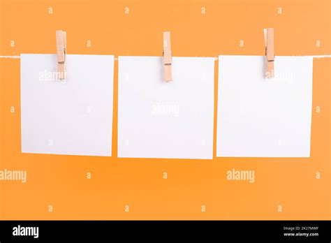 empty white sheets of paper in a row hanging on a string copy space
