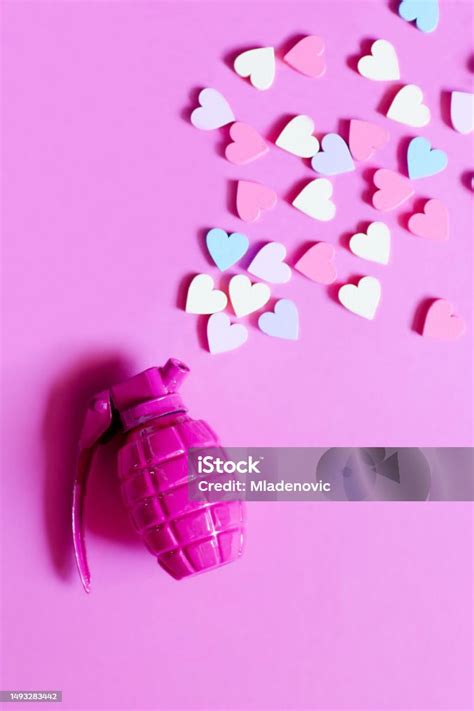 분홍색 장난감 수류탄 폭탄은 분홍색 배경에 여러 가지 빛깔의 작은 하트를 가지고 있다 전쟁 없는 평화와 삶의 개념 전쟁이 아닌 사랑을 하라 0명에 대한 스톡 사진 및 기타