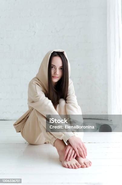 갈색 머리 유럽 소녀 에 스웨트 팬츠 과 A 후드 앉아 에 A 흰색 나무 바닥 에 A 밝은 방 백인종에 대한 스톡 사진 및 기타