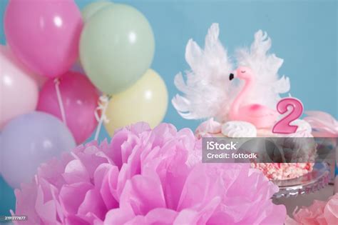 흰색과 분홍색 생일 케이크는 플라밍고 그림 깃털 날개 및 파란색 배경에 두 개의 촛불로 장식되어 있습니다 가로 이미지 엽서 생일 초대장 0명에 대한 스톡 사진 및 기타