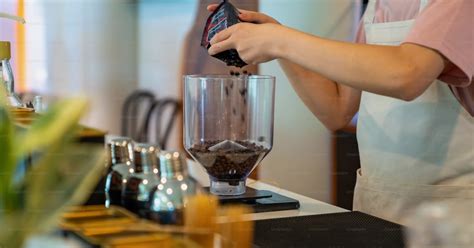 아시아 남자 커피 숍 파트 타임 직원은 커피 머신에서 뜨거운 커피를 양조합니다 커피 메이커에서 분쇄 커피로 에스프레소를 만드는