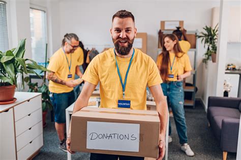 백그라운드에서 동료들과 골판지 상자를 들고 있는 자원봉사자의 초상화 기부함에 대한 스톡 사진 및 기타 이미지 기부함 남자 자선기부 Istock