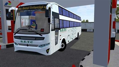 A White Bus Parked In Front Of A Gas Station With Red And White Stripes On The Side