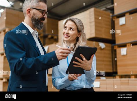 Female Warehouse Manager Talking With Logistics Employee In Warehouse Planning Transport Of