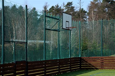 학교에서 볼 게임을위한 다기능 야외 놀이터 라인이있는 플라스틱 카펫에서 녹색 인조 잔디 농구 농구와 축구 목표 높은 그물과 가드레일을 잡는 주변 갈색에 대한 스톡 사진 및