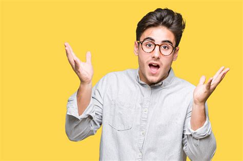 젊은 잘생긴 남자에 안경을 절연 배경 미친을 축 하 하 고 무기와 성공을 위한 흥분 비명 제기 및 오픈 눈 깜짝 놀라게 우승자