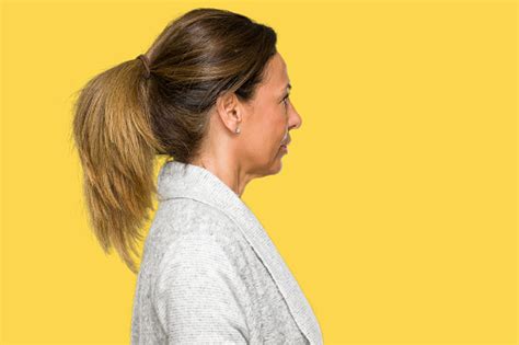 아름 다운 중 년 성인 여자 입고 겨울 스웨터 사이드로 보고 격리 된 배경 위에 긴장 자신감 미소와 자연 스러운 얼굴 프로필