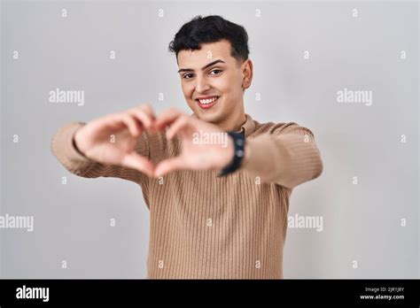 Non Binary Person Standing Over Isolated Background Smiling In Love Doing Heart Symbol Shape