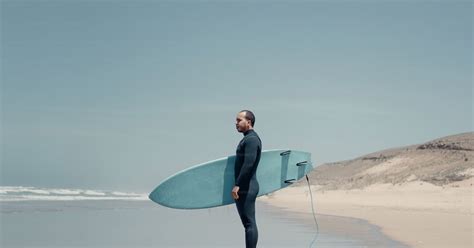 서핑보드를 들고 해변에 서 있는 남자 사진 Unsplash의 바닷가 이미지