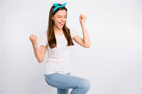 기쁘게 쾌활한 소녀 의 초상화 제기 주먹 예 복권 에 승리 상을 축하 캐주얼 스타일의 의상 데님 청바지 흰색 배경 위에 고립 T 셔츠에 대한 스톡 사진 및 기타 이미지