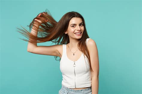 스튜디오에서 파란색 청록색 벽 배경에 고립 된 머리를 들고 가벼운 캐주얼 의류에 웃는 젊은 여자의 초상화 사람들은 진심으로 감정