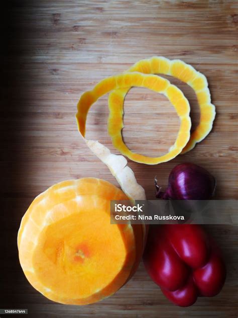 반 껍질을 벗긴 오렌지 버터넛 스쿼시의 식품 예술은 여전히 삶 긴 피부는 음악 노트 모양으로 말려 빨간 양파 나무 도마에 적갈색 파프리카 건강한 야채 다이어트의 개념 복사