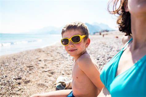 Мальчик с его матерью загорает на пляже Стоковое Изображение изображение насчитывающей малыш