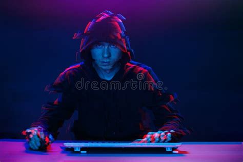 Hacker In The Hood Working With Computer Typing Text In Dark Room Image With Glitch Effect