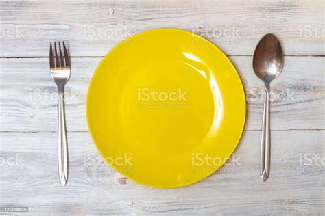 숟가락과 포크가 있는 빈 노란 접시가 흰색 테이블에 서 있습니다 웃옷에 대한 스톡 사진 및 기타 이미지 웃옷 접시 포크 Istock