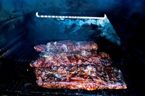 즙이 많은 갈비뼈 랙이 뒤뜰의 그릴에서 지글지글 끓습니다 스모키한 향이 나는 이 음식을 여러 부분으로 자르고 톡 쏘는 바베큐