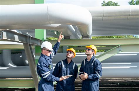 엔지니어 또는 공장 기술자 노동자 팀 그룹은 석유 화학 가스 파이프 라인 아래에 서 있으며 하나는 작업장의 파이프 라인을 가리 킵니다 25 29세에 대한 스톡 사진 및 기타