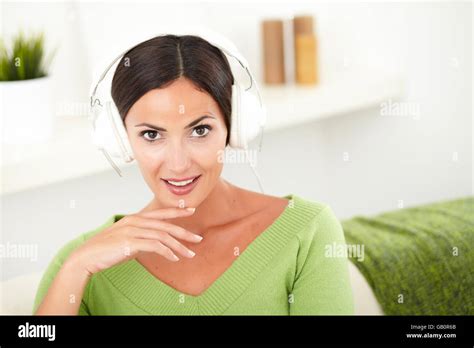 Surprised Young Woman Listening To Music While Touching Her Chin With