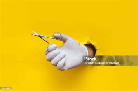 흰색 의료 장갑을 낀 남자의 손은 페디큐어와 매니큐어를 위해 작은 가위를 들고 있습니다 노란색 종이에 찢어진 구멍이있는 노란색