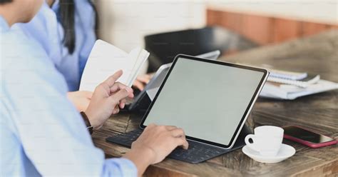 빈티지 사무실 위의 나무 회의 테이블에서 컴퓨터 태블릿 및 문서정보를 배경으로 작업하는 그래픽 디자이너 팀의 자른 이미지 사진 Unsplash의 태국 이미지