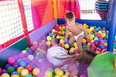 The Older Sister Plays With Her Younger Brother And Throws Small Balls At Him While Sitting In