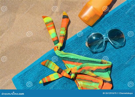 Soft Blue Beach Towel With Bottle Of Sunscreen Sunglasses And Colorful Bikini Bottom Flat Lay