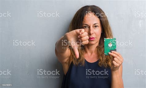 중세 스페인 여자 회색 그런 지 벽 성 난 얼굴 아래로 엄지 싫어 보여주는 음수 부호 거부 개념 하드 드라이브를 들고 서 갈색 머리에 대한 스톡 사진 및 기타 이미지