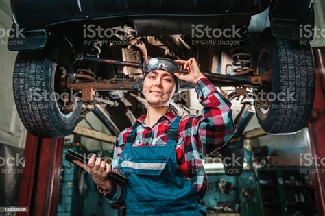 유니폼을 입고 안경을 들고 태블릿을 손에 들고 있는 젊은 여성 정비사가 승강장 차 밑에 서 있는 포즈를 취하고 있다 실내 하단