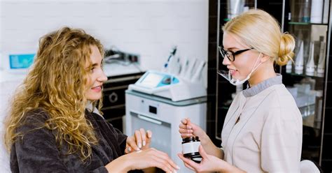 젊은 여성 미용사가 젊은 금발 여성 고객과 손 피부 관리 절차에 대해 이야기합니다 미용사는 특별한 크림을 추천합니다 사진 Unsplash의 뷰티 사이언스 이미지