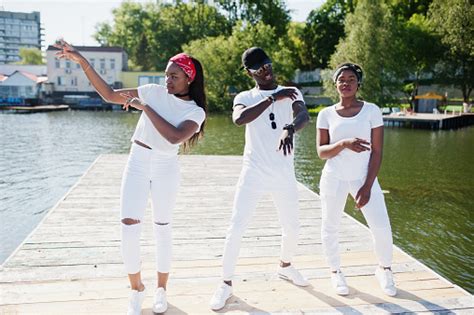 세 가지 세련 된 아프리카계 미국인 친구 비치에 부두에서 흰색 옷에 착용 Dab를 표시 합니다 젊은 흑인 들의 스트리트 패션