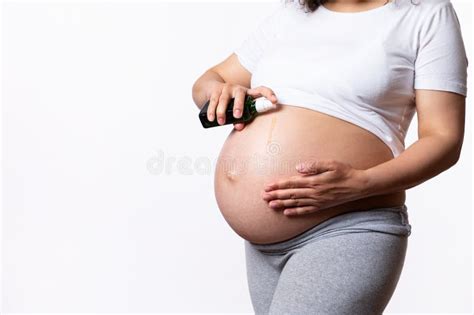 Close Up Pregnant Woman Rubbing Smoothing Cosmetic Oil Product On Her