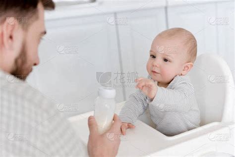 父亲喂养小儿子与婴儿奶瓶在厨房