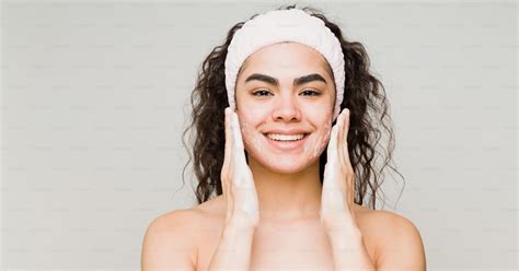 수건과 머리띠를 착용하고 페이셜 클렌저와 비누로 얼굴을 씻는 행복한 뷰티 모델 사진 Unsplash의 여성 이미지