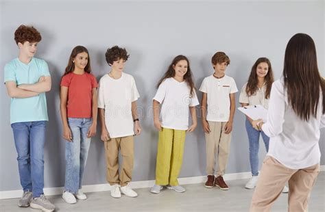 Cheerful School Students Standing In Row Listening To Female Teacher Or Psychologist In