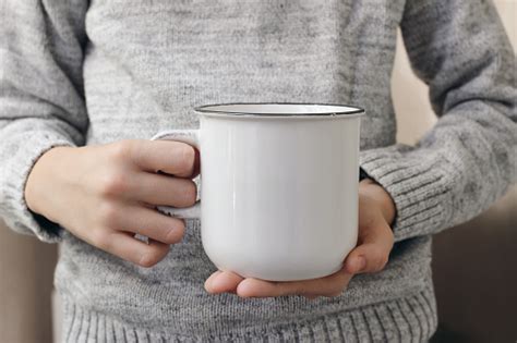 손의 클로즈업 흰 차 컵을 들고 있는 손가락 빈 Cearmic 머그잔 모형 흐릿한 배경 선택적 초점 커피 타임 겨울 정물화 회색 니트 스웨터를 입은 어린이 크리스마스 음료